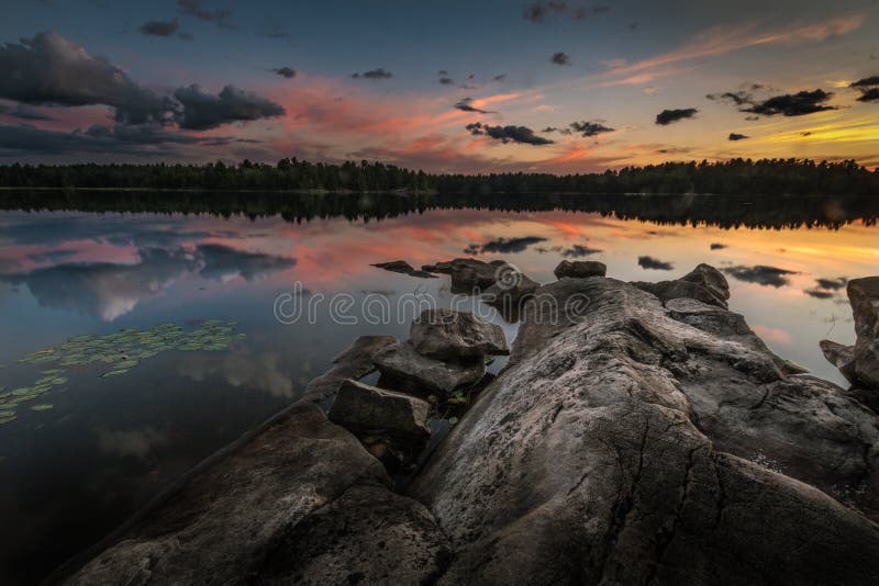 A Setting Sun with Clouds Reflected on a Smooth Lake. Stock Photo ...