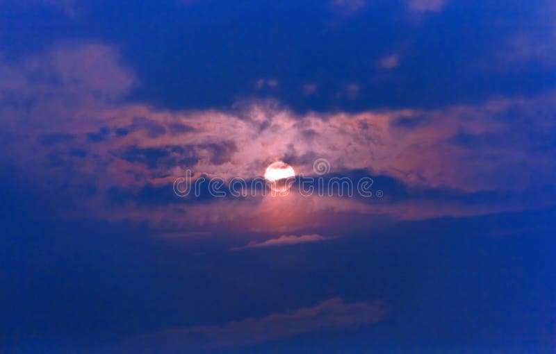The Setting Sun on the Dark Blue Sky Hiding in the Clouds Stock Image ...