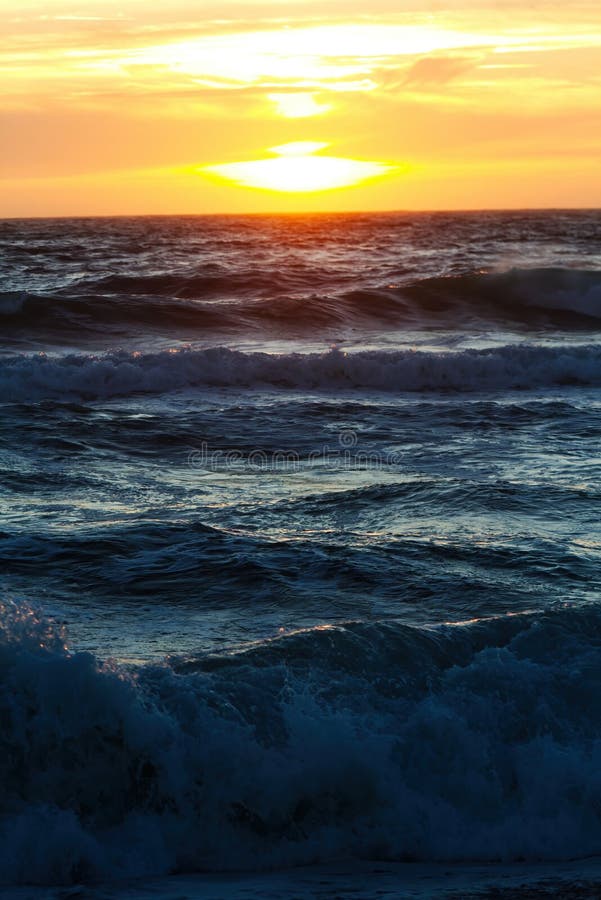 Setting Sun in Yellow Cloud Sky Over Ocean Waves Stock Photo - Image of ...