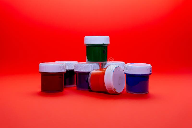 Brightly Colored Paint Containers Arranged on a Vibrant Red Background ...