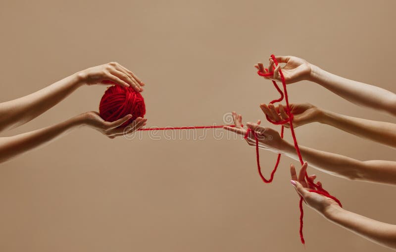 Several Hands Interacting with a Red Yarn Ball, Pulling and Twisting ...