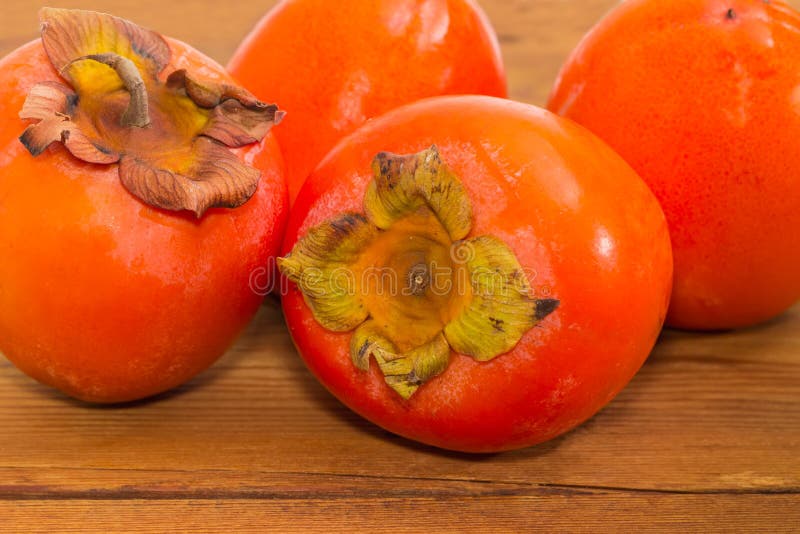 Several Persimmons on Wooden Surface Closeup Stock Photo - Image of ...