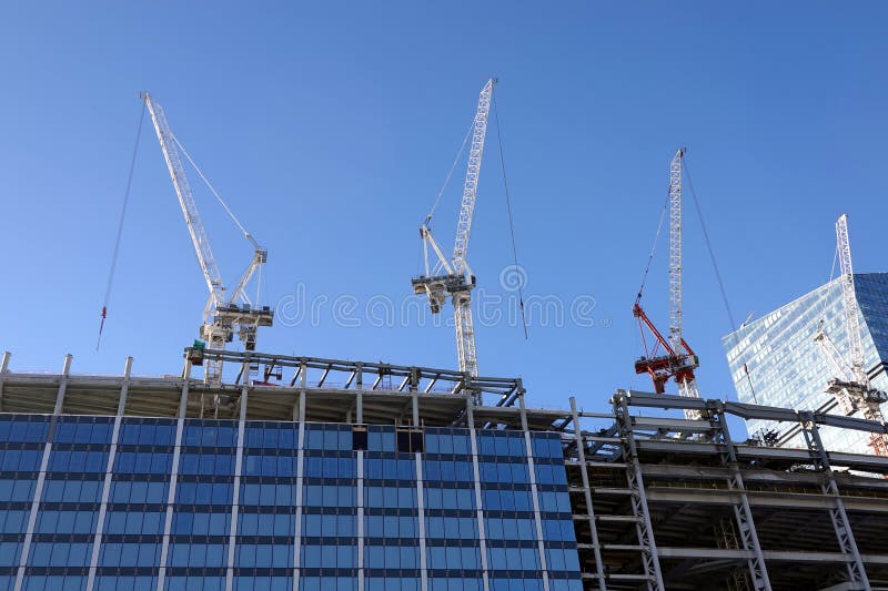 Several Tower Cranes are Building a Modern Tall Skyscraper Against ...
