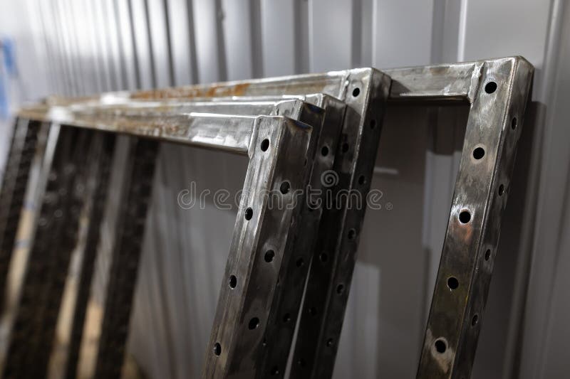 Several Welded Metal Frames with Drilled Holes are Stacked Against a ...