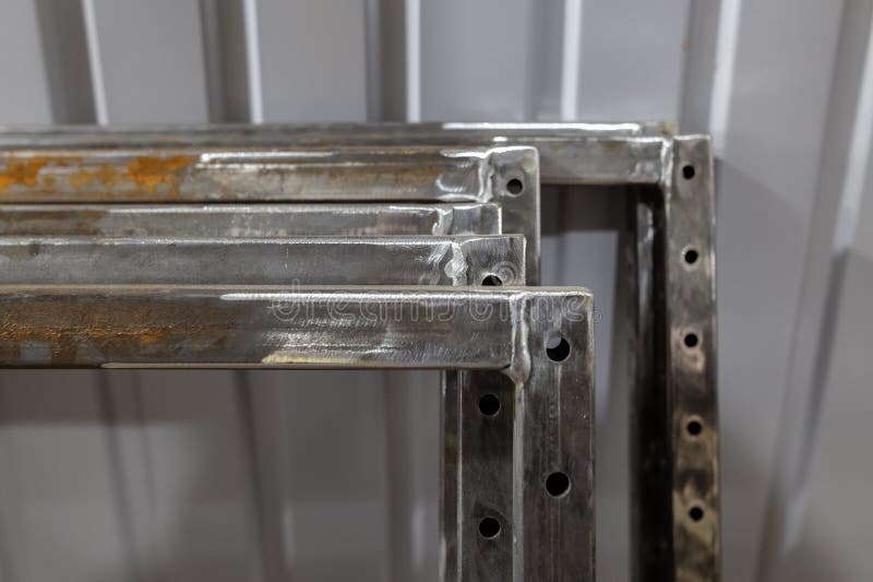 Several Welded Metal Frames with Drilled Holes are Stacked Against a ...