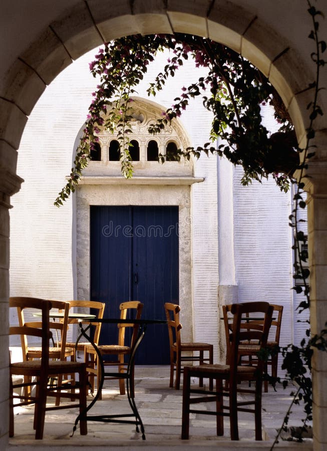 Several Wooden Chairs in Front of a White Building and Some Hanging ...