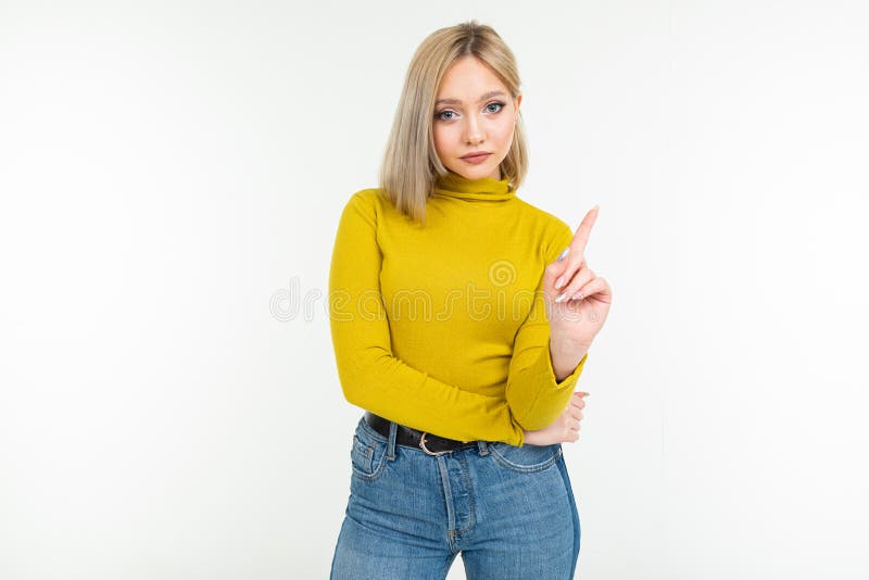 Blond Girl In A Tight Fitting Lemon Blouse And Jeans Waves Her Hands In Denial On A White