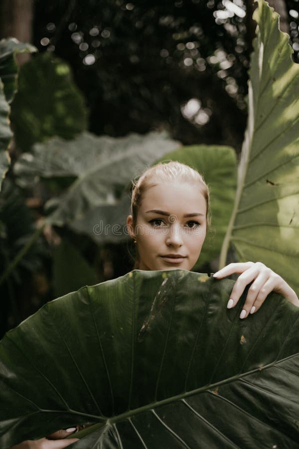 Beautiful Woman Hiding Behind The Palm Leaves In The In The Tropical