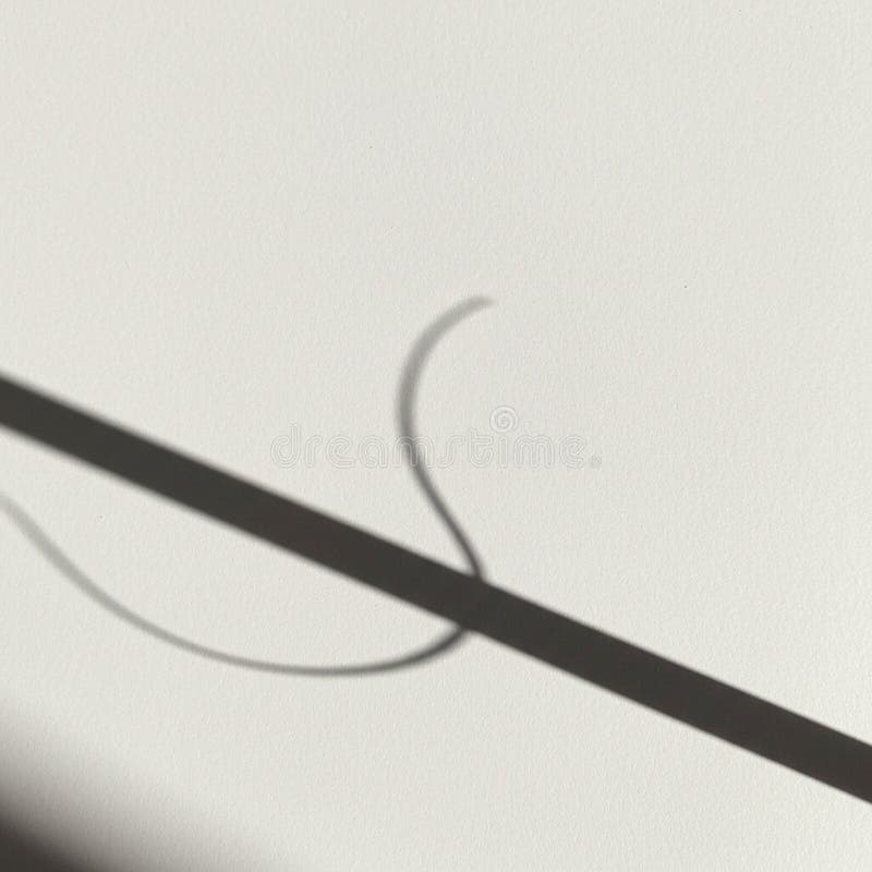 A Shadow is Cast on a Light-colored Surface, Featuring a Straight ...