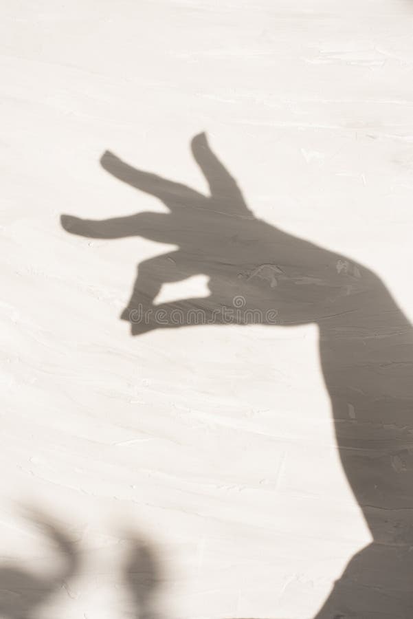 Shadow of a Hand with Two Fingers Clasped on a Light Textured Surface ...