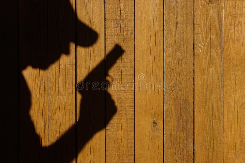 Man with a Gun in Shadow on a Wooden Background Stock Photo - Image of ...