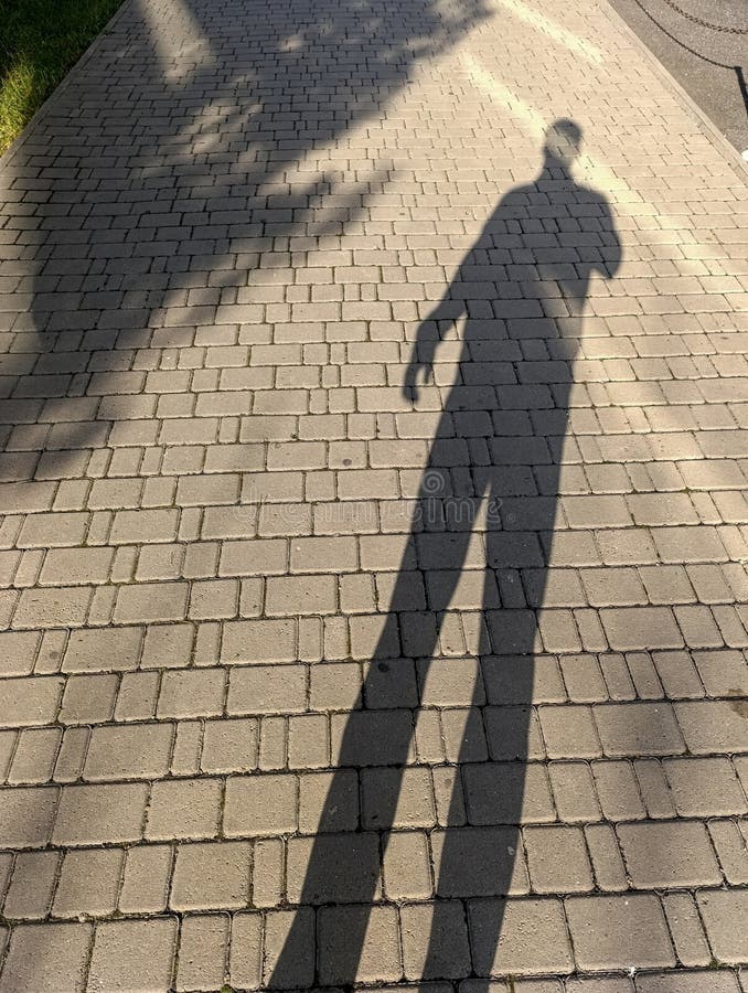A Shadow of a Person Walking Down a Brick Sidewalk Stock Photo - Image ...
