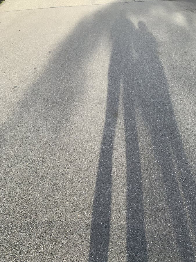 The Image Captures a Shadow Cast on a Dark Gray Asphalt Surface. Stock ...