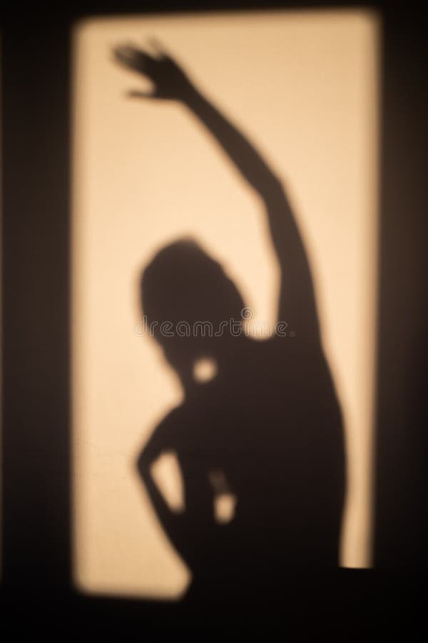 The Shadow of a Woman Exercising at Home at Dawn. Stretching at Home ...