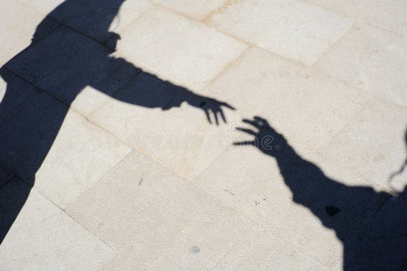 Shadows of Two Hands Reaching Out on Sunlit Pavement Stock Image ...
