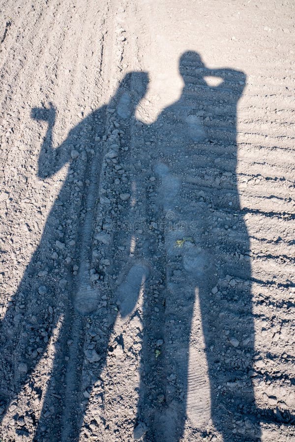 Shadows of Two People on Freshly Plowed Ground. Stock Image - Image of ...