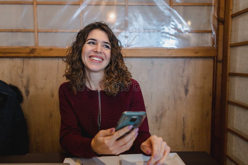 Shallow Focus of a Curly Woman Smiling with Her Smartphone Her Hands ... Shallow Focus of a Curly Woman Smiling with Her Smartphone Her Hands ...