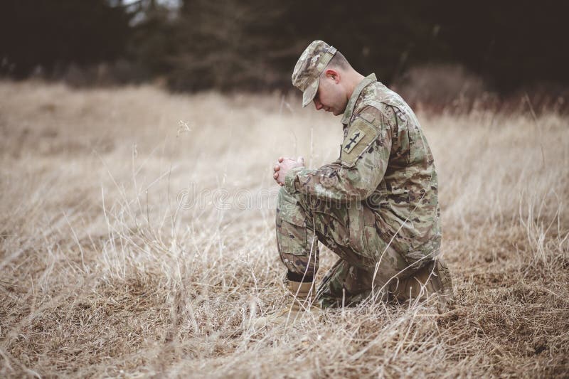 Shallow Focus Shot of a Young Soldier Praying while Kneeling on a Dry ...