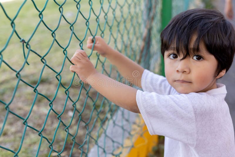 Shallow Focus of a Young Hispanic Boy Leaning on a Chain-link Fence in ...