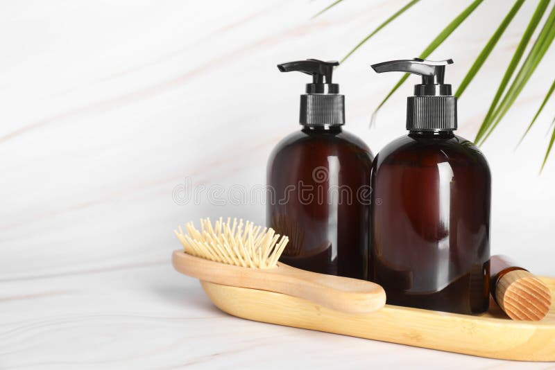 Shampoo Bottles, Wooden Brush and Essential Oil on White Marble Table ...