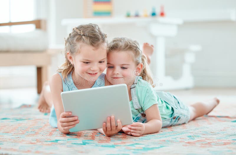 Sharing Screen Time. Two Adorable Girls Using a Digital Tablet while ...