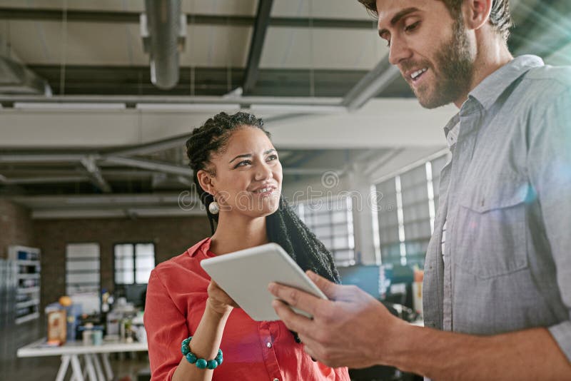 Sharing Some Invaluable Ideas. Two Colleagues Using a Digital Tablet ...