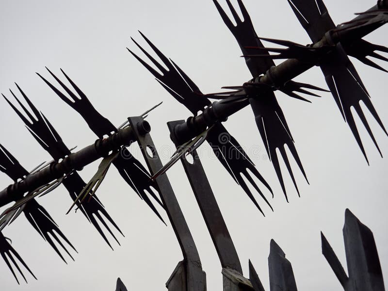 Sharp, Angled Barbed Security Fence Silhouetted Against a Cloudy Sky ...