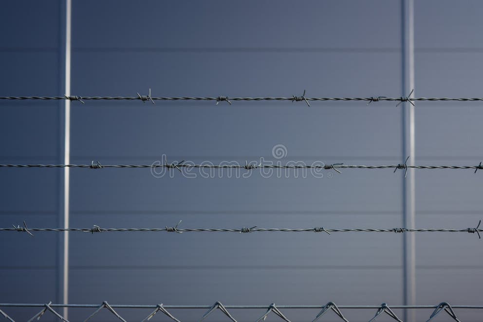 Sharp Metal Barbed Wire in Front of a Blue Warehouse.. Stock Image ...