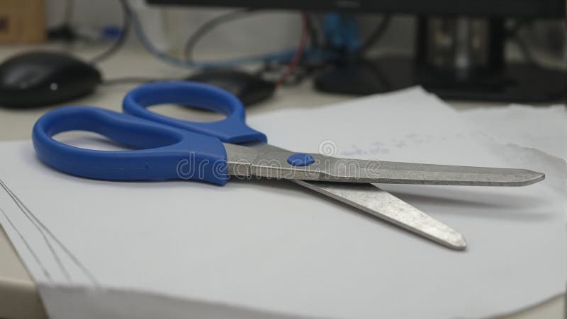 Sharp Silver Scissors with Blue Handles on a Wooden Desk Next To a ...