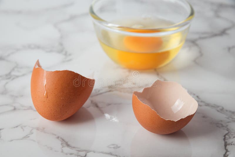 Shell with Egg and Open Egg in a Bowl before Cooking on White Marble ...