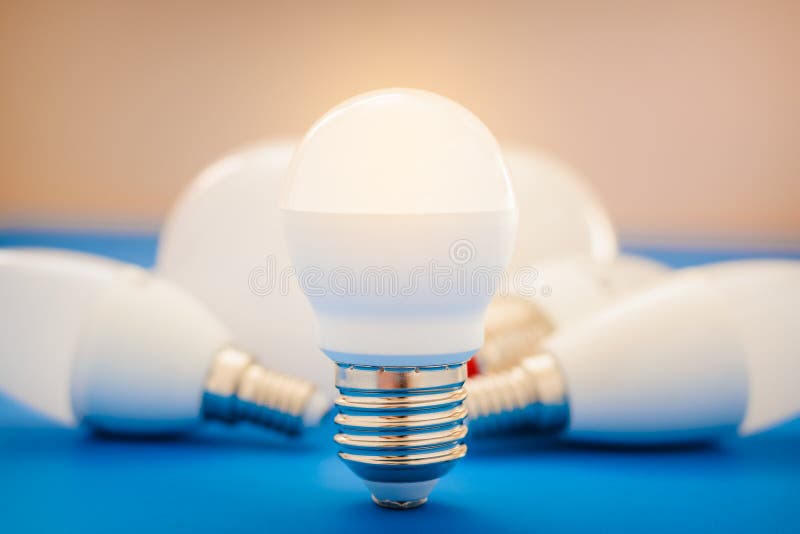 Shining LED Lamp and Bunch of Other Light Bulbs on Blue Background ...
