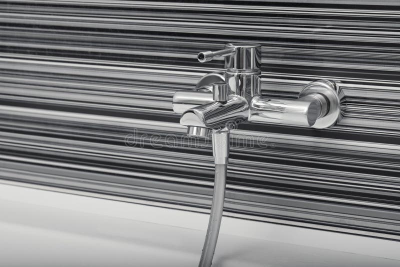 Shiny Water Tap Installed On Black And White Wall Above Bathtub Stock