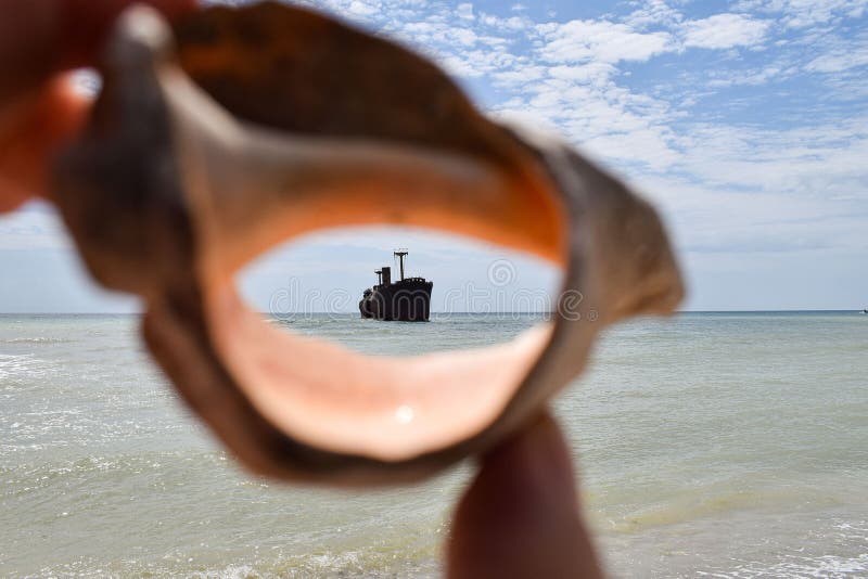 Shipwreck through a Seashell on a Beach Stock Photo - Image of ...