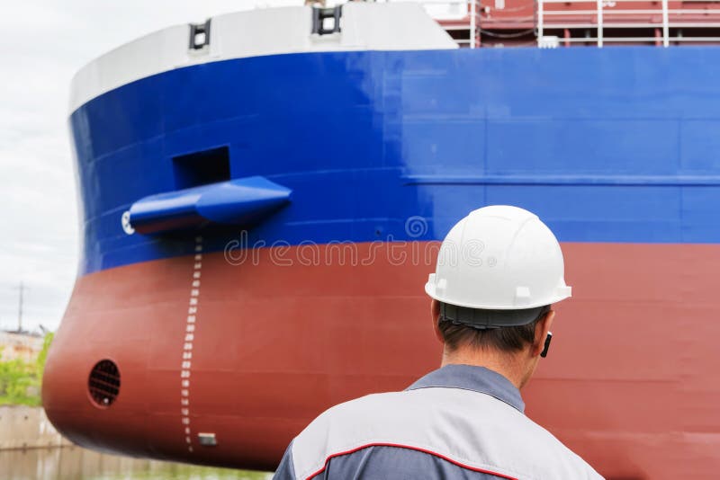 Shipyard. a Worker in Front of a Large Ship during Launching. Back View ...