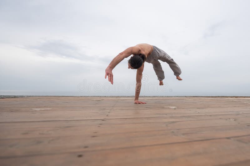 Shirtless Caucasian Man Doing Backflip on Pebble Beach. Stock Photo ...