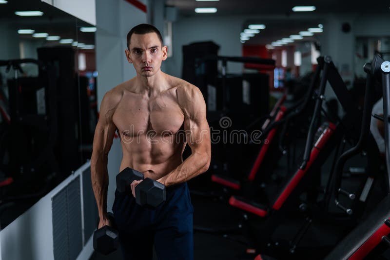 Shirtless Man Doing Bicep Exercises with Dumbbells in the Gym. Stock ...