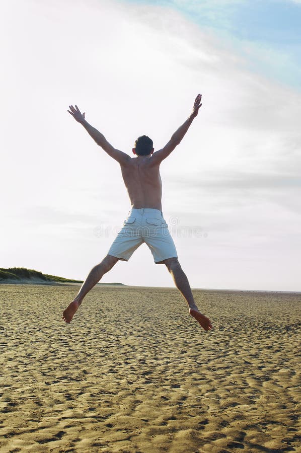 Shirtless Man Doing Star Jump on Beach Stock Photo - Image of norfolk ...