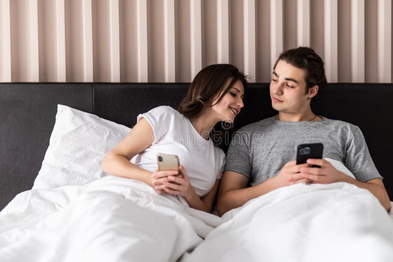 Shocked Woman Noticing Her Husband Checking His Smartphone And Texting