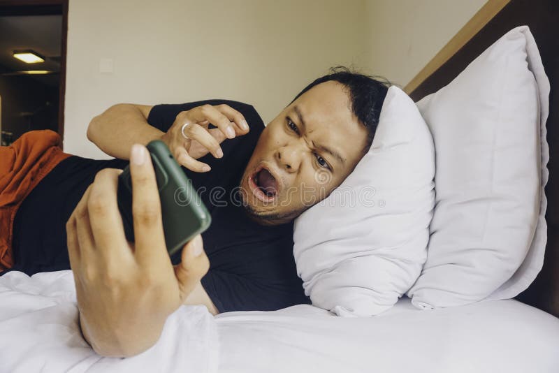 Shocked Young Man Checking on Her Phone while Lying in Bed Stock Image ...