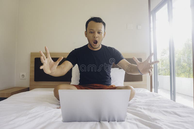 Shocked Young Man Checking on His Laptop while Sitting in Bed Stock ...