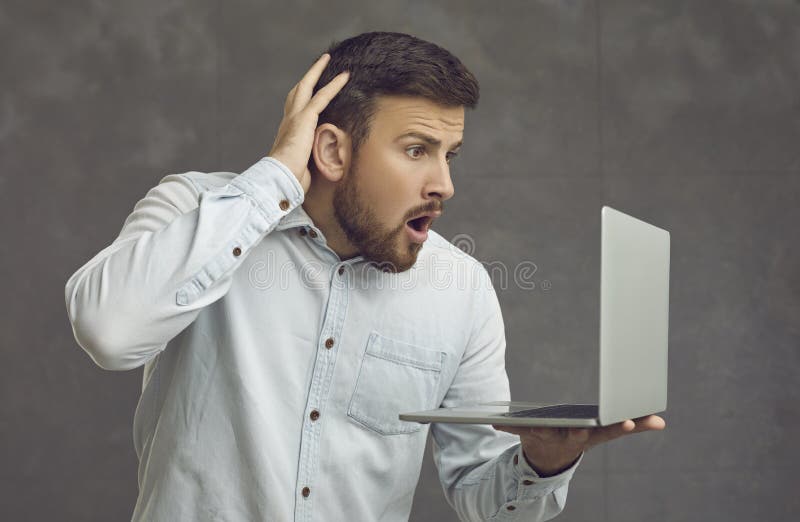 Shocked Young Man Looking at Screen of Laptop Computer that he S ...