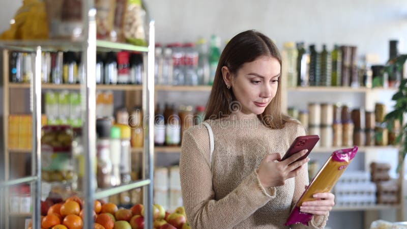 In Shop Young Woman Scans QR Code and Take Reading on Spaghetti Package ...