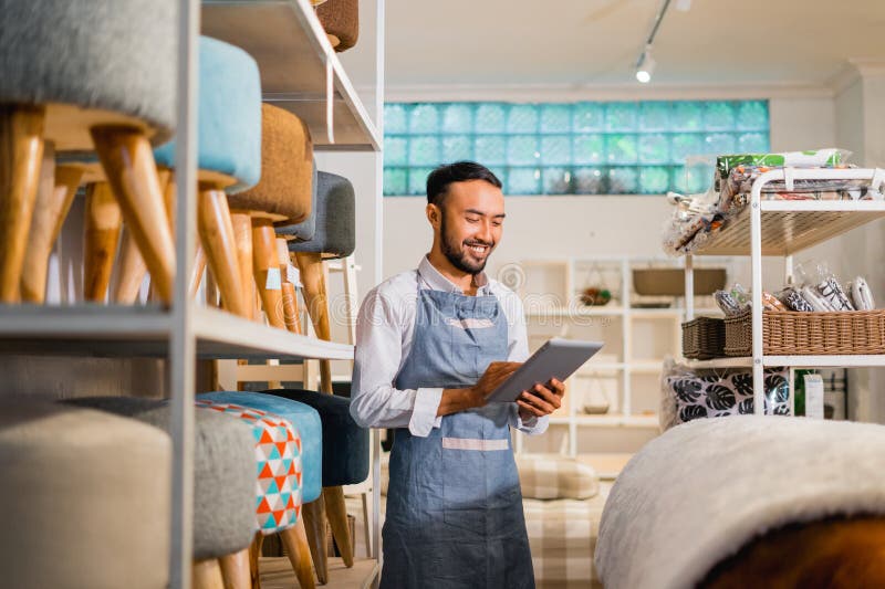 Shopkeeper Man in Apron Using a Tablet in a Furniture Store Stock Image ...