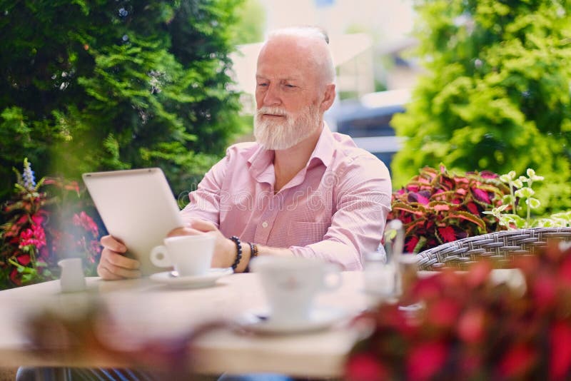 Old Man Sitting at Table with Tablet Outdoors in Nature Stock Photo ...