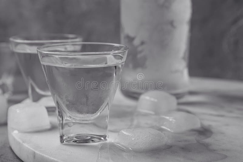 Shot Glasses and Bottle of Vodka with Ice Cubes on Marble Board ...