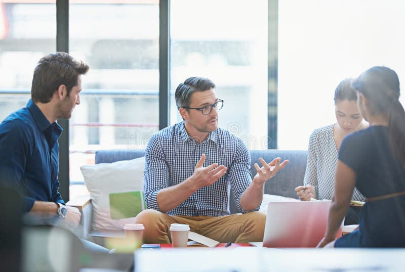 Solutions are a Group Effort. Shot of a Group of Office Workers Talking ...