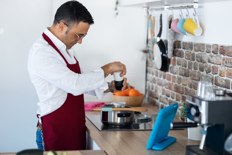 Handsome Man Cooking while Following a Recipe on the Digital Tablet in ...