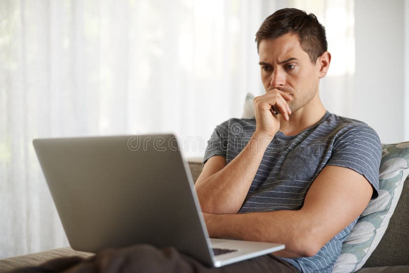 Now Thats a Thinker. Shot of a Handsome Young Man Using His Laptop at ...