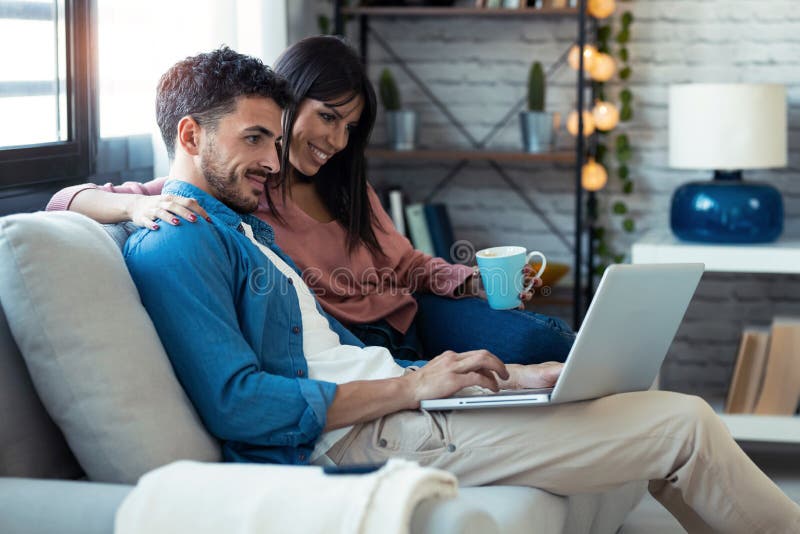 Happy Beautiful Couple Using Computer while Sitting on the Couch at ...