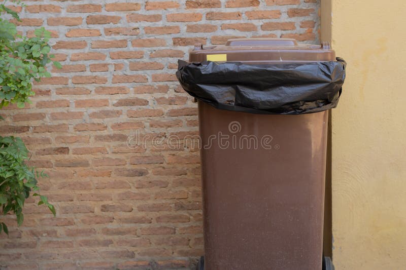 Shot of a Large Brown Trash Bin Setting Over Orange Brick Wall with ...